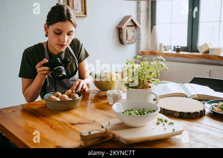 Young food stylist photographing through digital camera in studio Stock ...