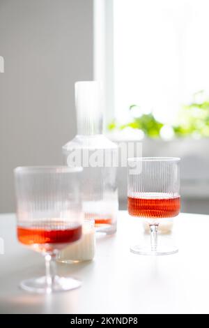 Rose wine in trendy ribbed wineglasses and decanter on white table ...