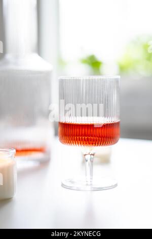 Rose wine in trendy ribbed wineglasses and decanter on white table ...