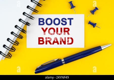 BOOST YOUR BRAND - inscription on a notebook and cup with coffee on a ...
