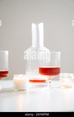 Rose wine in trendy ribbed wineglasses and decanter on white table ...