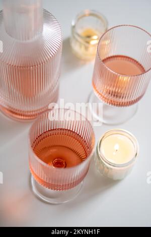 Rose wine in trendy ribbed wineglasses and decanter on white table ...
