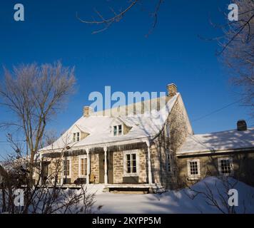 Old 1700s two story Canadiana style fieldstone home through trees in ...