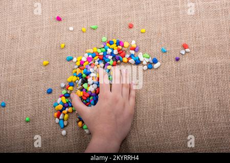 Colorful little pebbles in hand and on canvas ground Stock Photo - Alamy