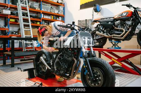 Mechanic woman repairing custom motorcycle on factory Stock Photo - Alamy
