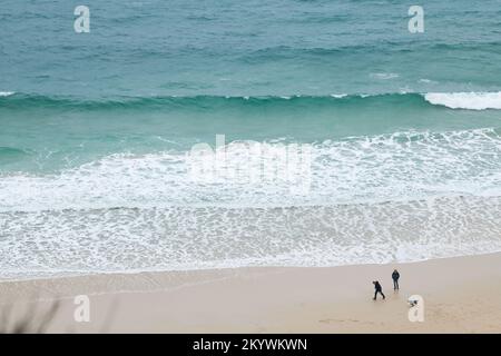 A couple with their dog on the beach at Porthcurno Bay, Cornwall ...