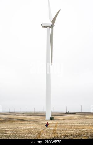 Two people walk toward wind turbines under the blue sky at Atlanterra ...