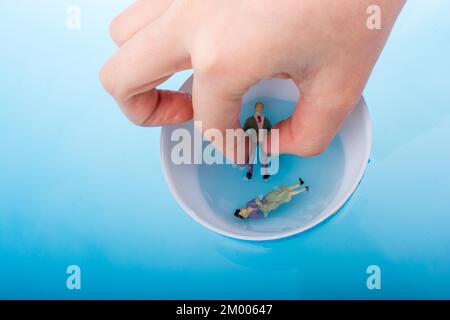 Little model globe with figurines floating in blue water Stock Photo ...