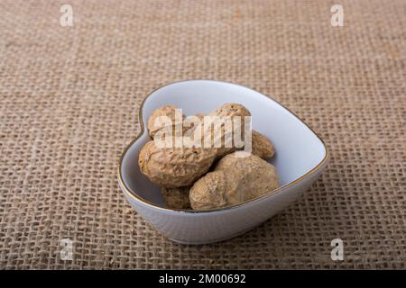 Peanuts in a heart shaped plate on canvas background Stock Photo - Alamy