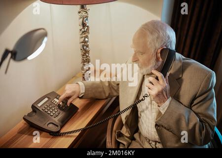 A gray-haired gentleman calling to the room service Stock Photo - Alamy