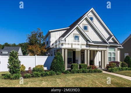 The front view of a cottage craftsman style white house with a triple ...