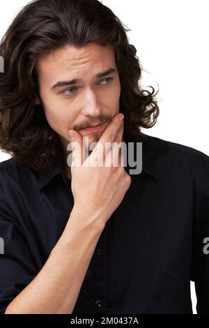 Pondering the options. A young man looking upwards thoughtfully while ...