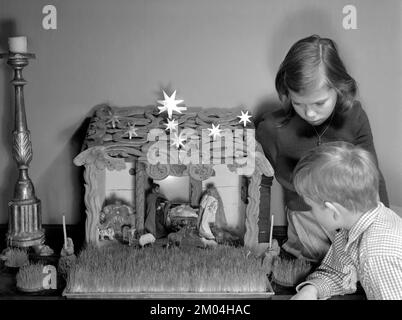 Christmas in the 1950s. Two children with a nativity scene, infant ...
