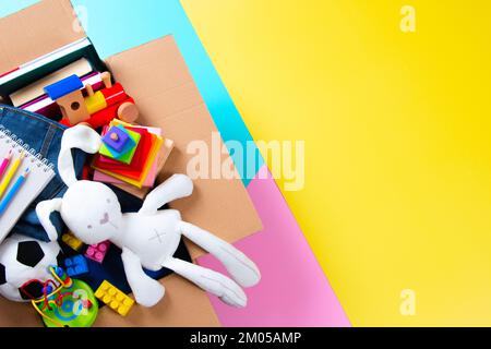 Donations box with kid toys, books, clothing for charity on colorful ...