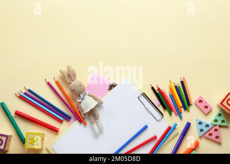 Blank paper sheet with pencils and felt-tip pens on beige background ...