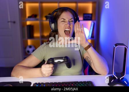 Brunette hispanic girl wearing headphones very happy pointing with hand ...