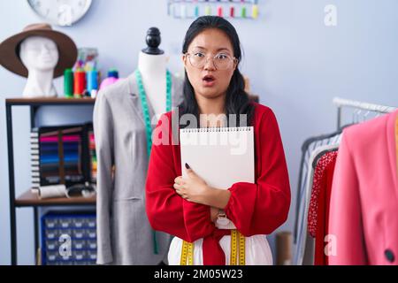 Young brunette woman standing by manikin at small business holding i am ...