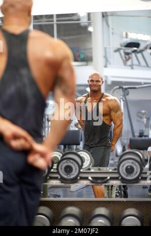 bodybuilder checking his physique in the mirror at a competition in ...
