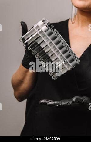 Нand of cosmetologist in black latex glove on white background in ...