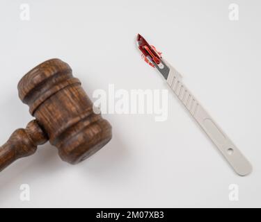 A scalpel covered in blood and a judge's wooden gavel Stock Photo - Alamy