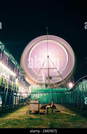 A vertical long exposure shot of a Ferris wheel at night with colorful ...