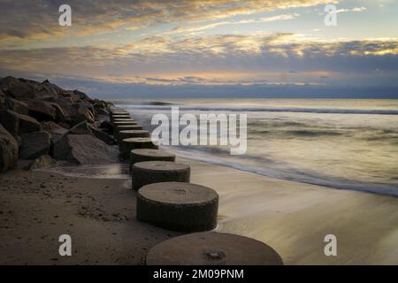 A long exposure of waves at Fort Fisher State Park at a pink and scenic ...