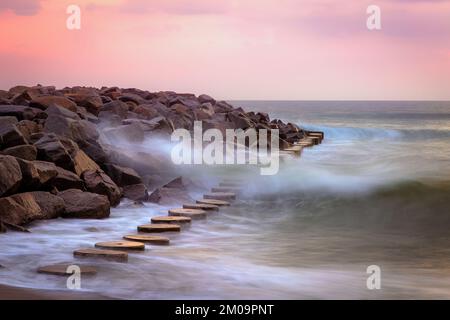 A long exposure of waves at Fort Fisher State Park at a pink and scenic ...