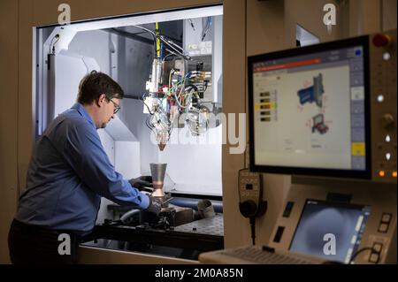 Ditzingen, Germany. 30th Nov, 2022. An employee of laser specialist Trumpf uses a model of a ...