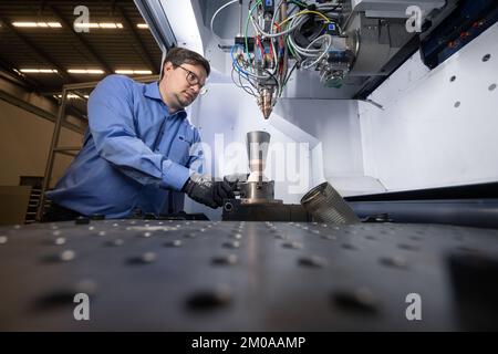 Ditzingen, Germany. 30th Nov, 2022. An employee of laser specialist Trumpf uses a model of a ...