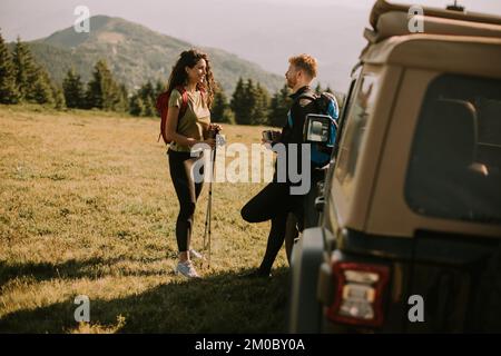 Smiling young couple preparing hiking adventure with backpacks by ...