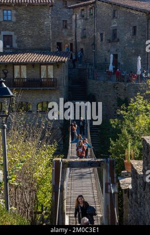 People crossing the suspension bridge of Rupit and old houses in the ...