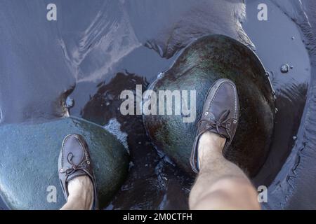 male feet in top siders on green stones over water Stock Photo - Alamy