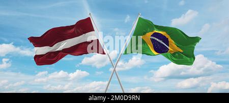 Latvia and Brazil flags waving together in the wind on blue cloudy sky ...
