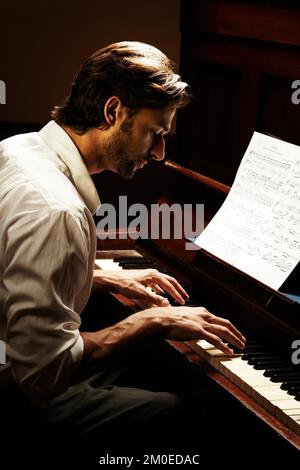 Making beautiful music. Profile of a handsome man playing the piano ...