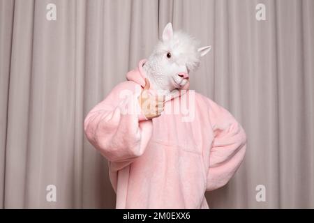 Person in pink hoodie with lama head showing gestures on studio wall ...