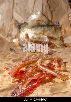 Pieces of oily dried salted fish on crumpled craft paper. View from ...