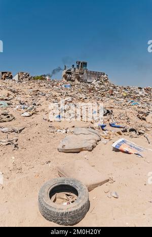A soil compactor, and two trailers dumping trash at an active landfill ...