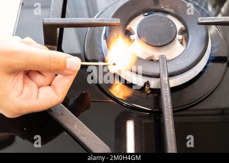 Hand turns on the gas burner on the gas stove Stock Photo - Alamy