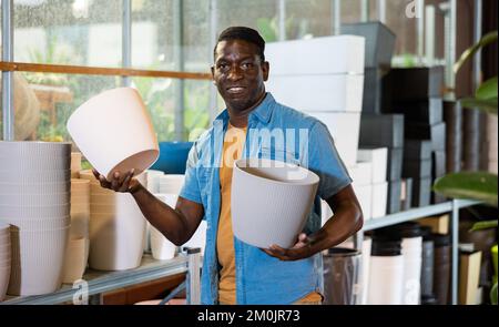 African american man chooses flower pots for indoor plants Stock Photo ...