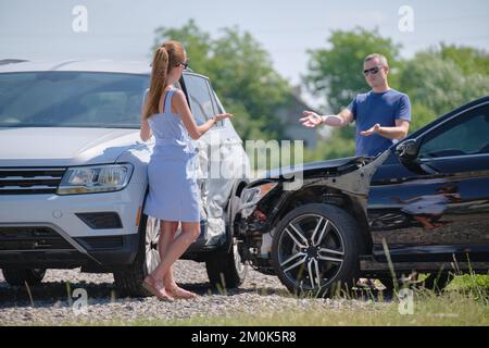 Angry woman and man drivers of heavily damaged vehicles arguing who is ...