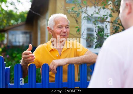 Elderly man discussing with neighbour beside house Stock Photo - Alamy