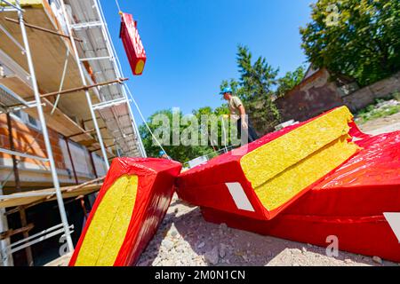 Worker on scaffold elevator insulating wall facade of new building ...