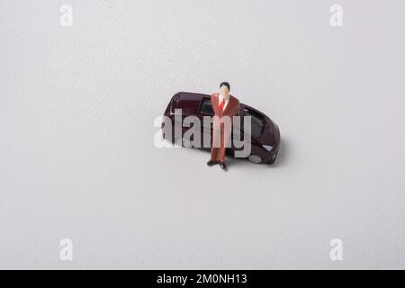 Tiny figurine of man before a miniature car Stock Photo - Alamy