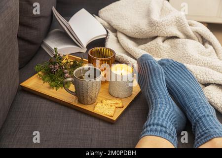 Soft photo of a woman`s legs in woolen blue socks on the sofa with a ...