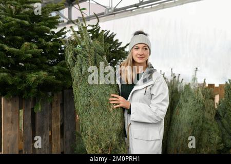 A girl buying a Christmas norman tree in a shop Stock Photo - Alamy