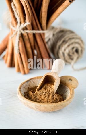 A small dish of cinnamon powder with a bunch of sticks in behind Stock ...