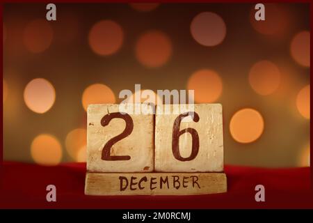December 26 vintage wooden block calendar on red fabric, festive bokeh ...