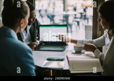Three bussinesspeople looking at statistics and charts for their recent ...