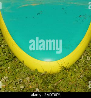 A blue and yellow surfboard put on the grass Stock Photo - Alamy