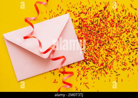 Top view of serpentine on envelope with gift bow on yellow background ...